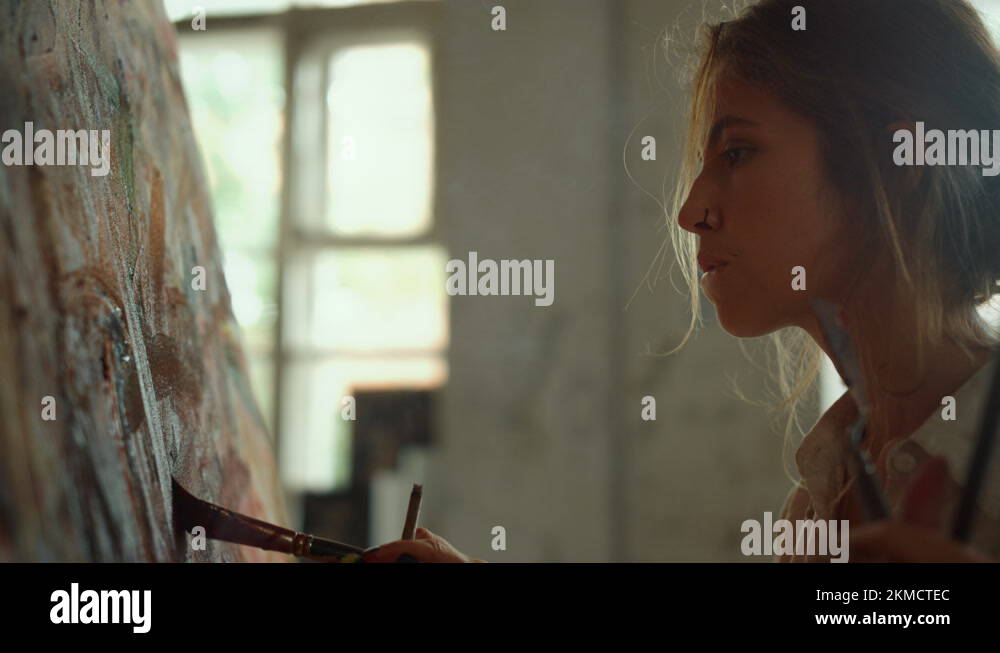 Serious woman painting at workplace. Focused painter using oil paints ...