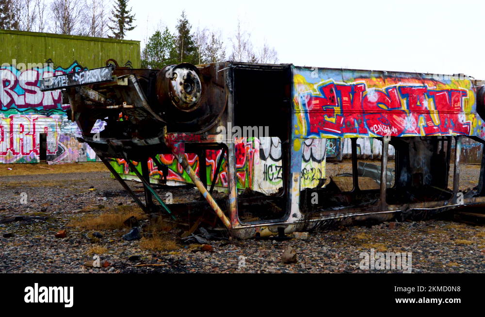 Burnt down buss covered in graffiti and stripped of tires. Panning shot ...