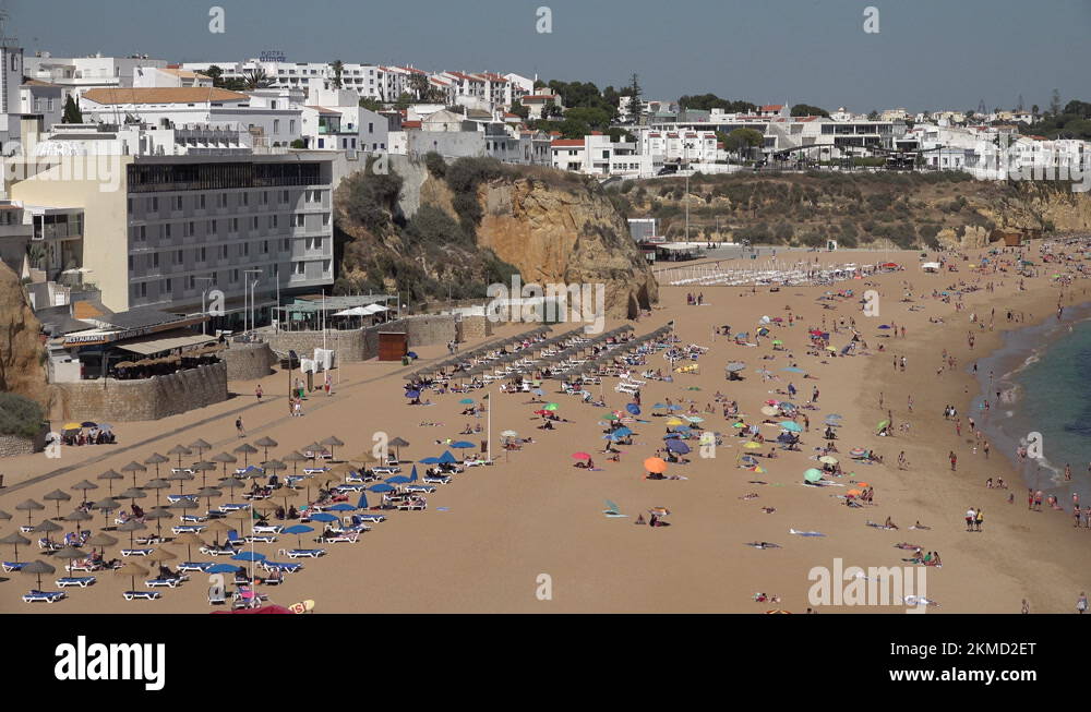 Hotels and houses on rocky cliffs, people visit beach Albufeira ...