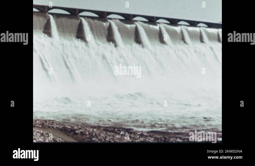 1960s: Water rotates model turbine. Water spills over a dam. Metal ...