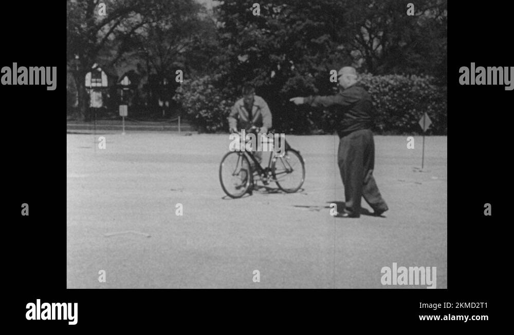 1950s: Older brother cycles between taped lines and comes to a stop ...