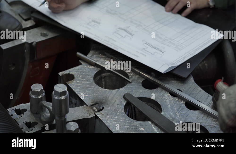 Two Workers are Discussing a Technical Drawing. A Controller is Making ...