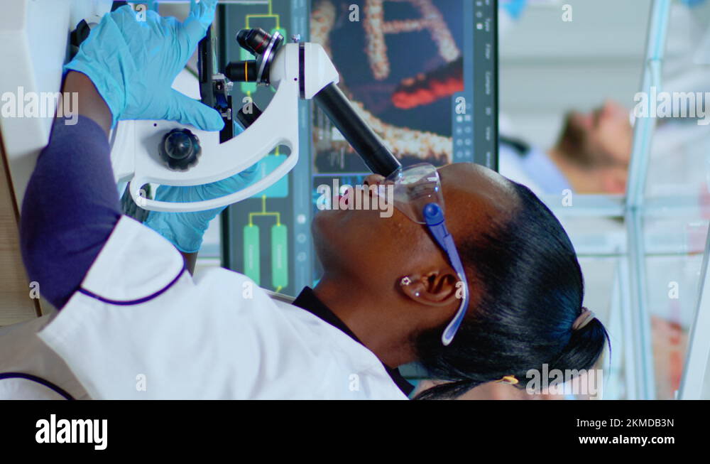 Vertical video: African woman scientist using microscope in modern lab ...