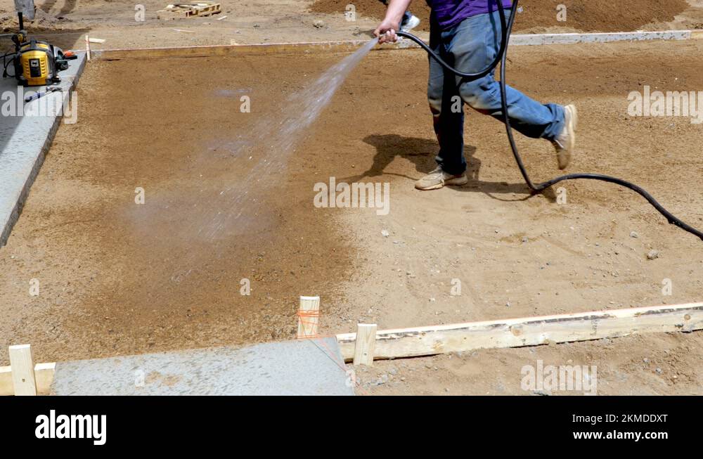 Spraying water on driveway dirt in preparation for new concrete Stock ...