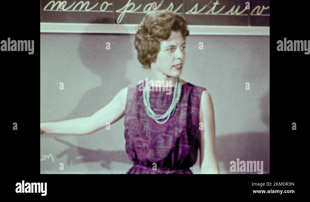 1970s: Boy enters classroom full of children. Teacher standing at ...
