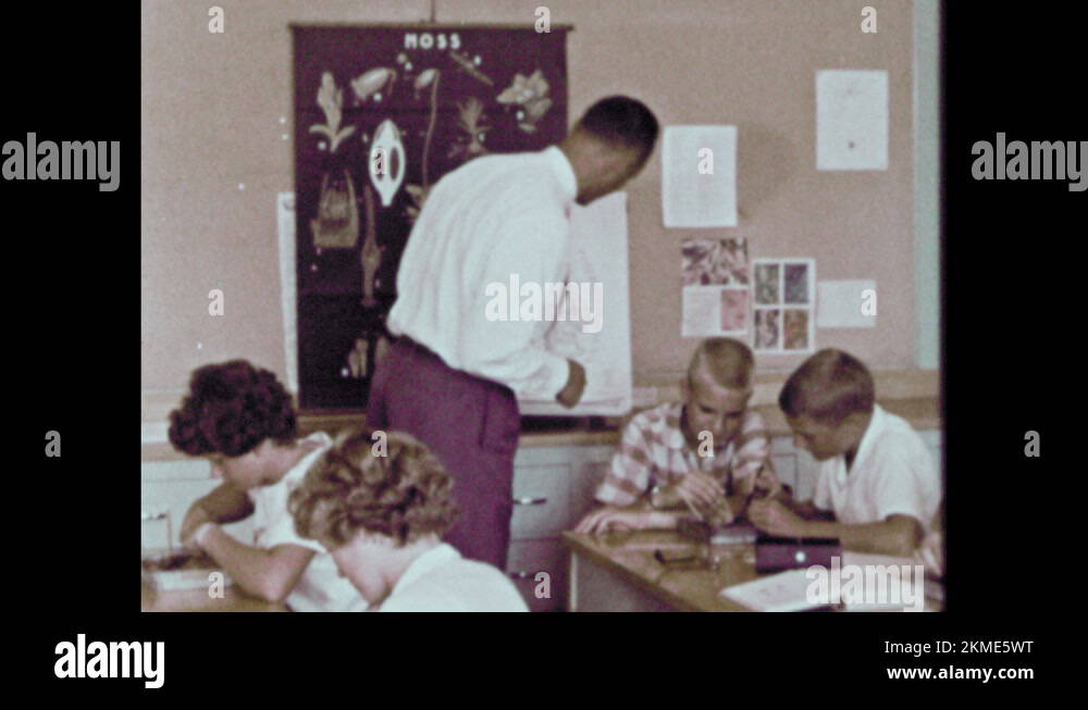1960s: Students in classroom talk, laugh. Students raise hand, teacher ...