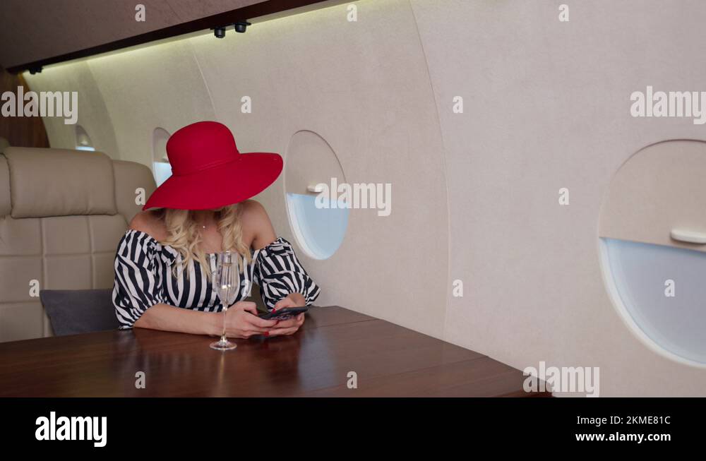 an elegant lady in a big red hat is flying to business aviation with a ...