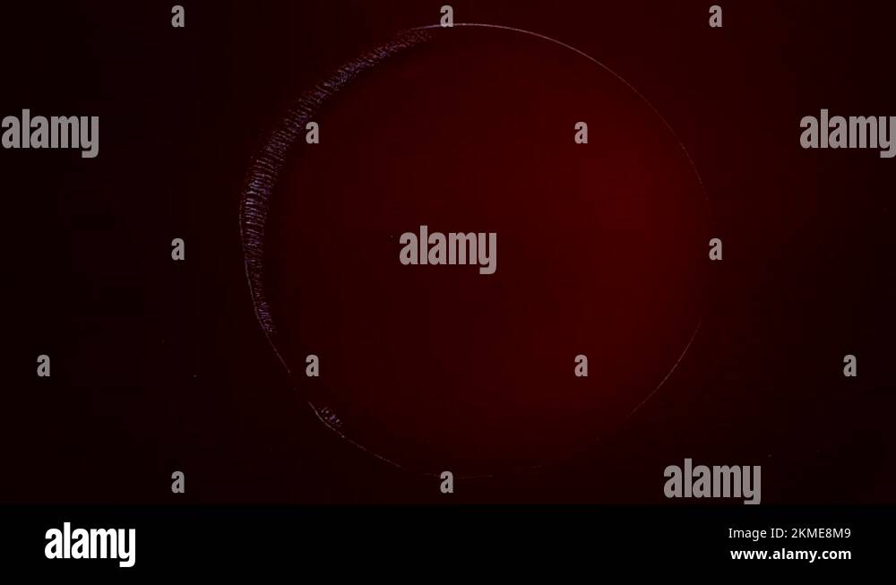 From out of a dark red background emerges a dark red orb that grows in ...