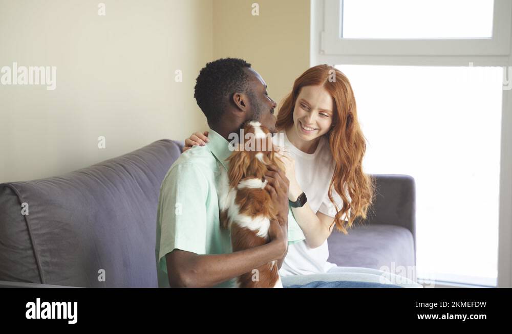 An attractive red-haired woman and a dark-skinned young man are hugging ...