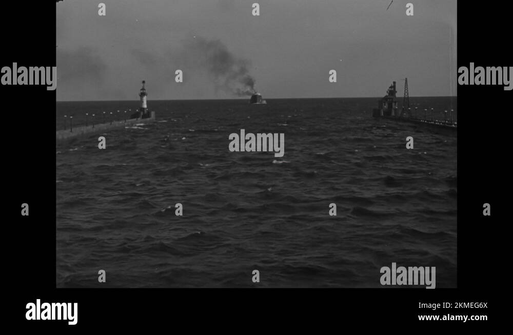 1940s: On lift at ship port as lift rises up. Cargo ship approaches ...