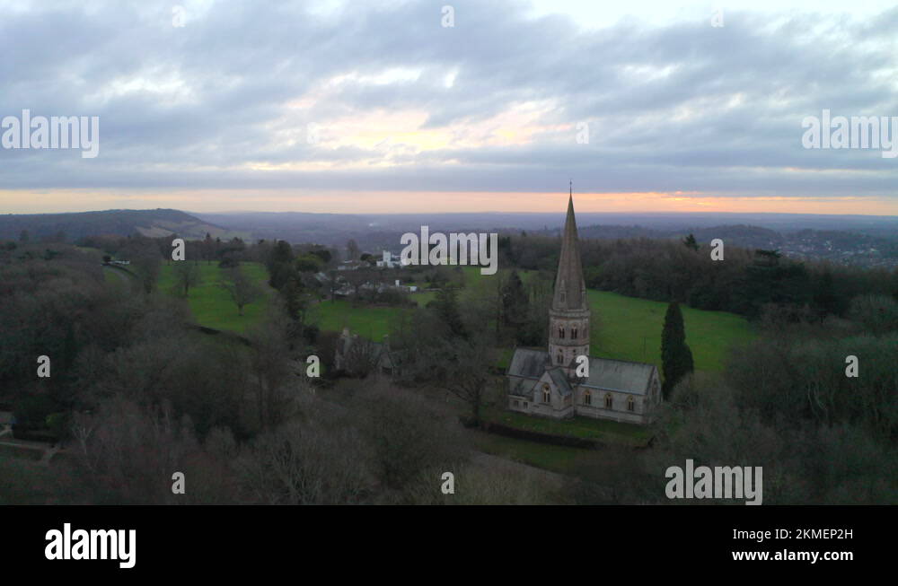 An aerial shot flying past an old English church on a hill in Ranmore ...