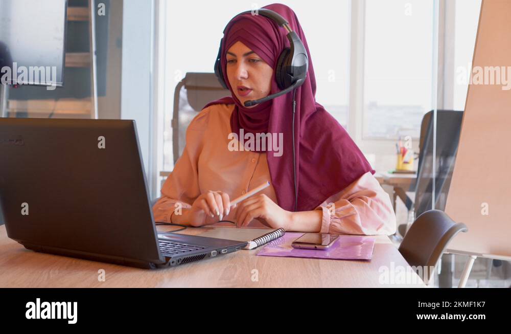 Portrait of smiling young islamic woman in hijab with microphone and ...