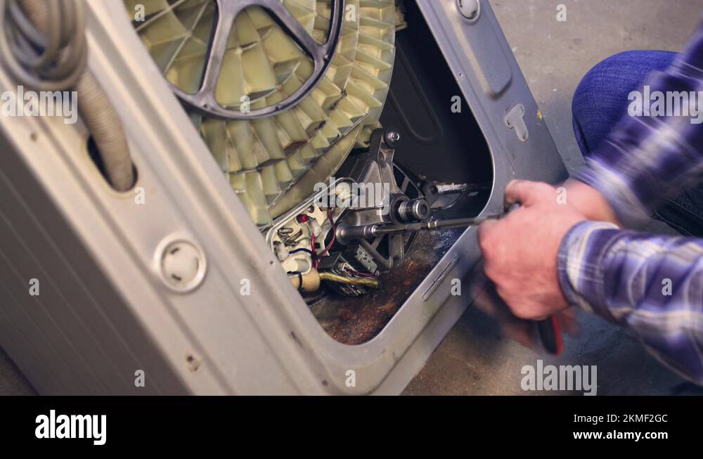 Men's hands turn the bolts with the end wrench in the washing machine ...