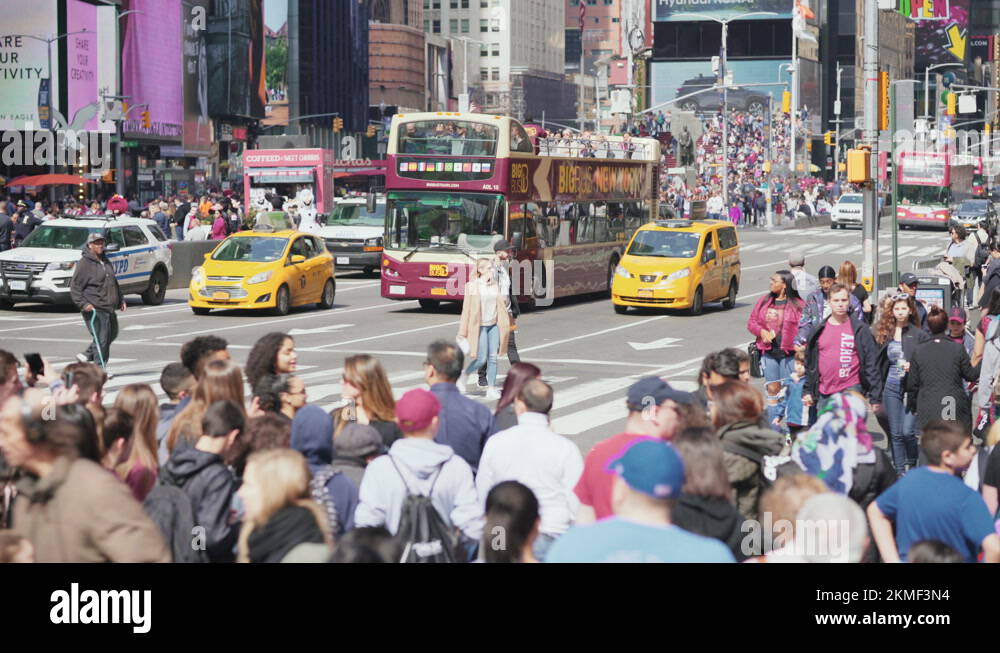 Crowd of people walk in Times Square. Car, bus and taxi transportation ...