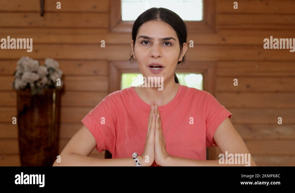 Portrait shot of an Indian girl doing namaste gesture while looking at ...