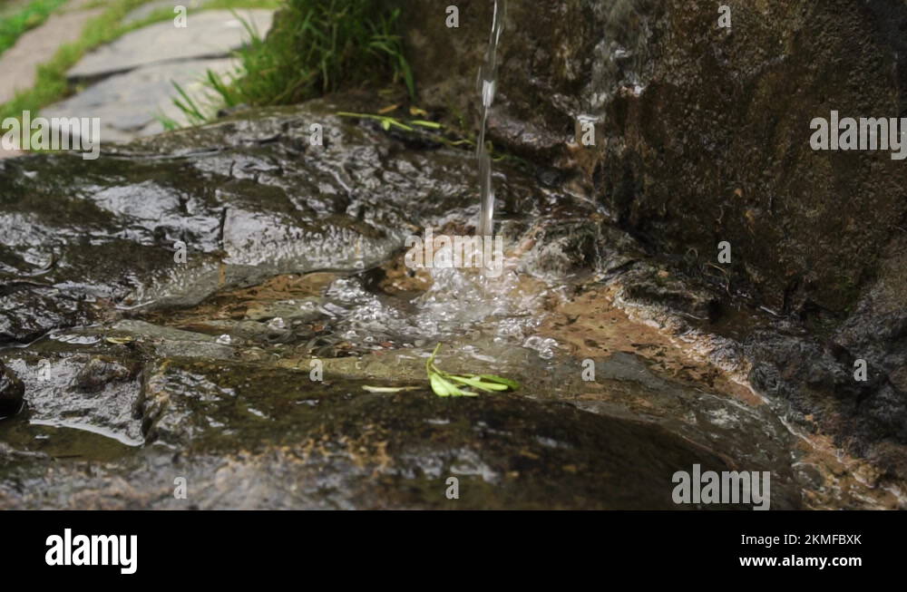 Natural mineral water from a clean mountain spring flows into a wet ...