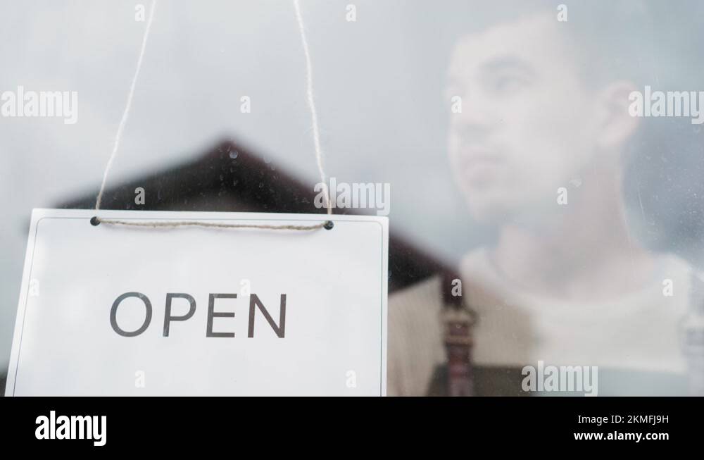 Waiter turn open close sign entrance door while reopening cafe during ...