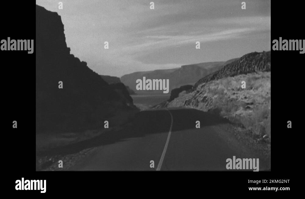 1930s: A car drives down a highway surrounded by rocky outcroppings. The road Stock Video ...