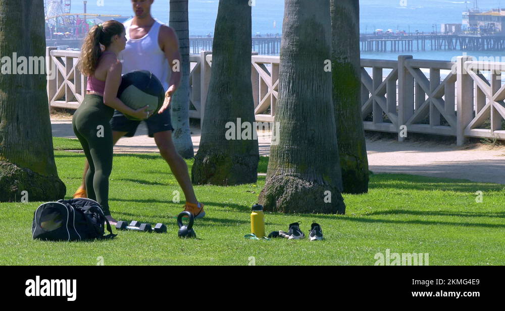 Young woman with her personal trainer doing yoga fitness exercising on ...