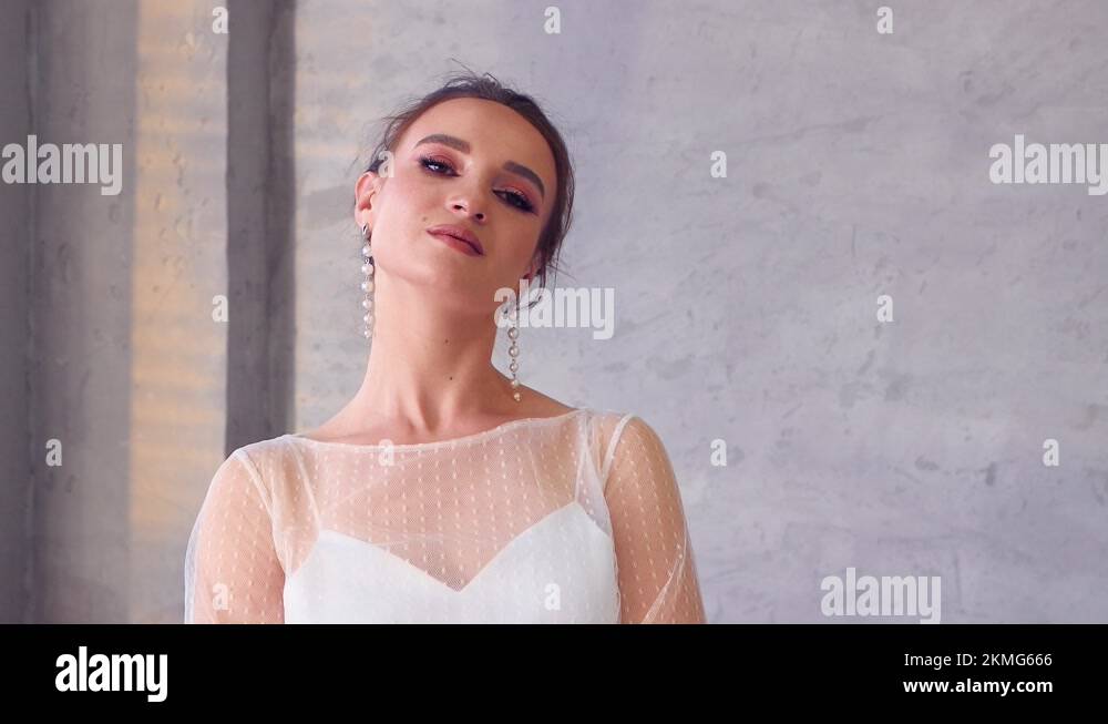 The girl in a white dress poses for the photographer turning her face ...