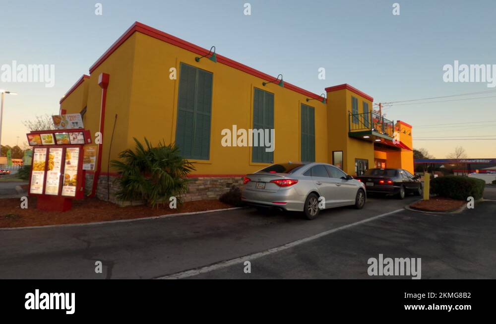Pan of Popeyes fried chicken restaurant drive thru line people in cars ...