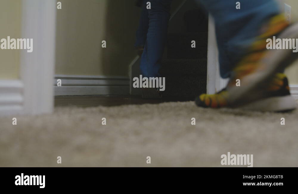 Three people’s feet following each other toward staircase ...