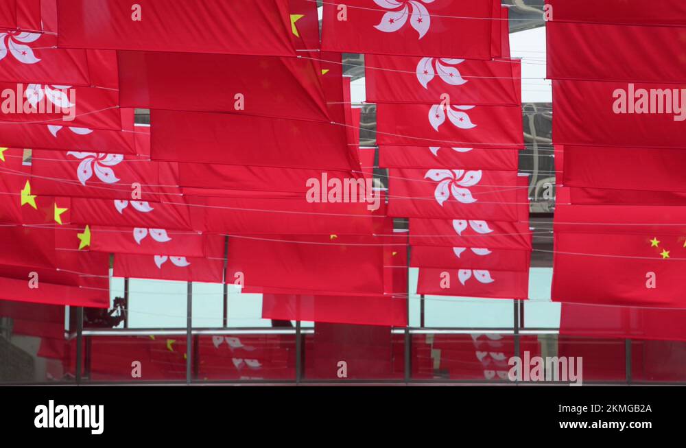 Commuters walk through a pedestrian bridge as flags of the People's ...