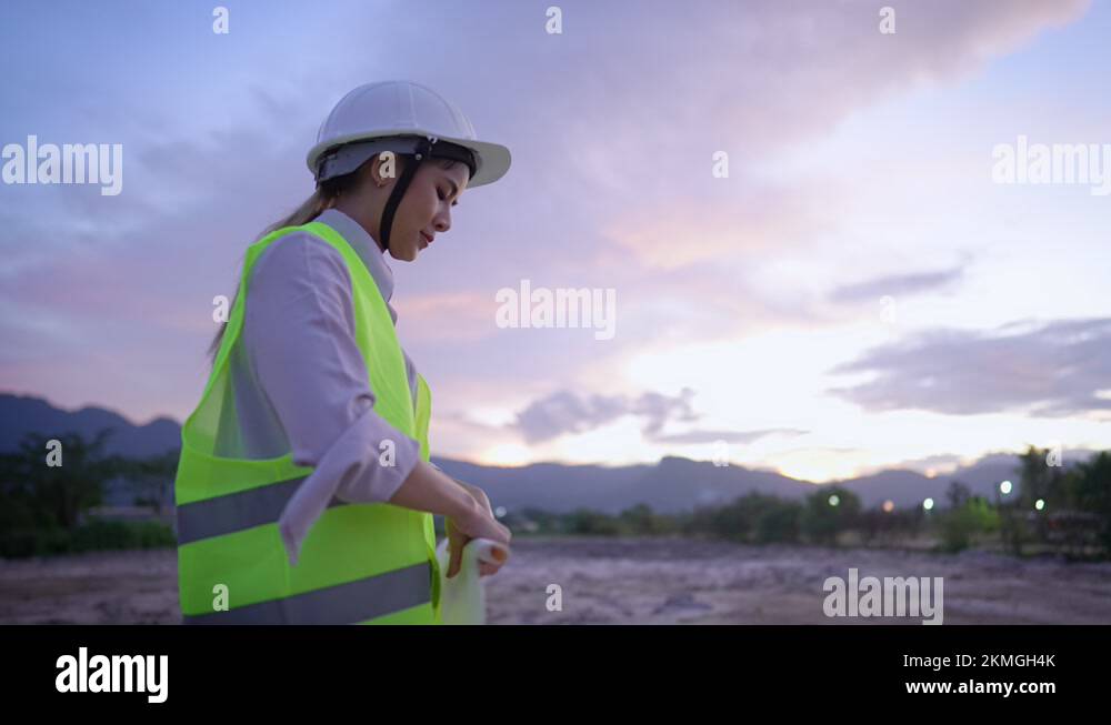 Young tired female construction worker folding a blueprint paper, over ...