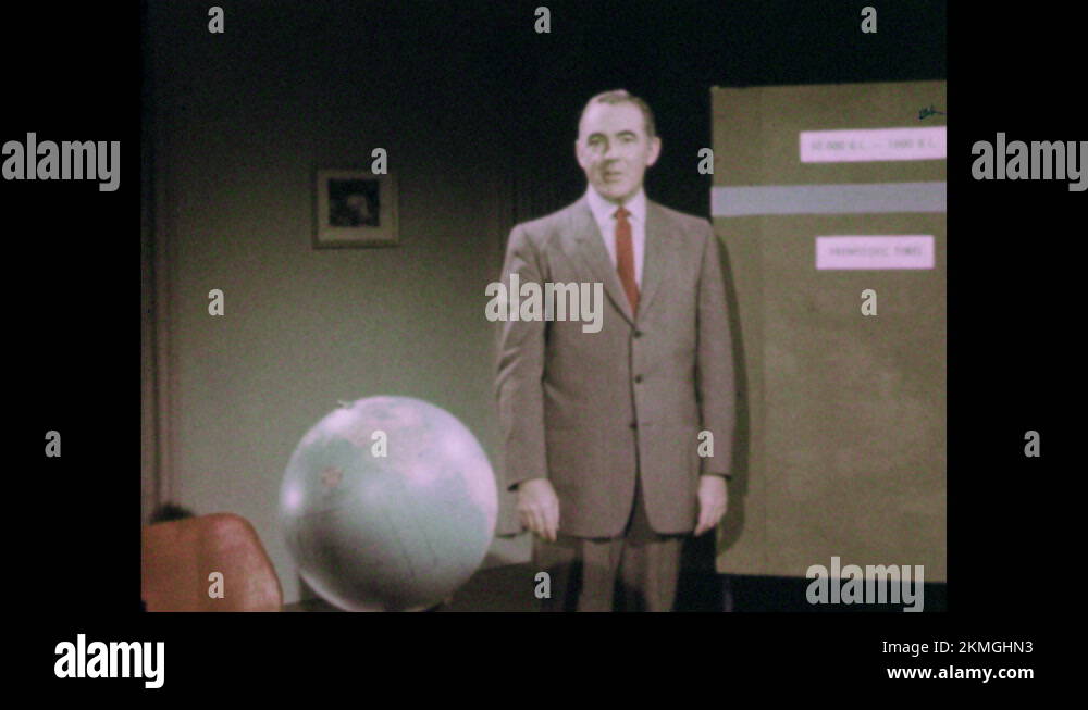 1950s: Man in suit and tie in front of timeline and globe. Man holds up ...