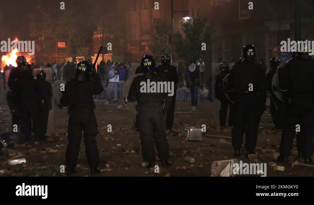 Metropolitan riot police stand and face incoming missiles from rioters ...