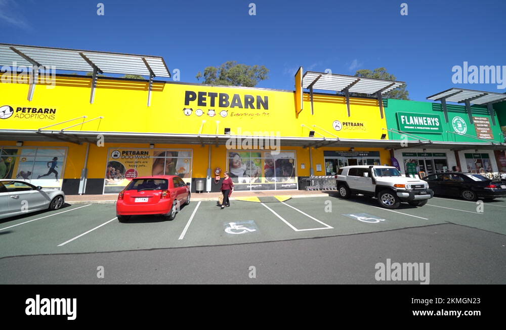 Petbarn store yellow facade and parking lot with people, dolly forward ...