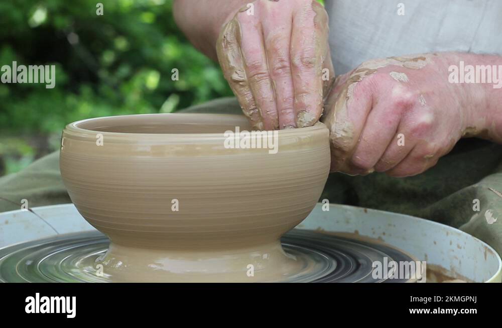 male potter of Caucasian ethnicity makes brown clay pot on an automatic ...
