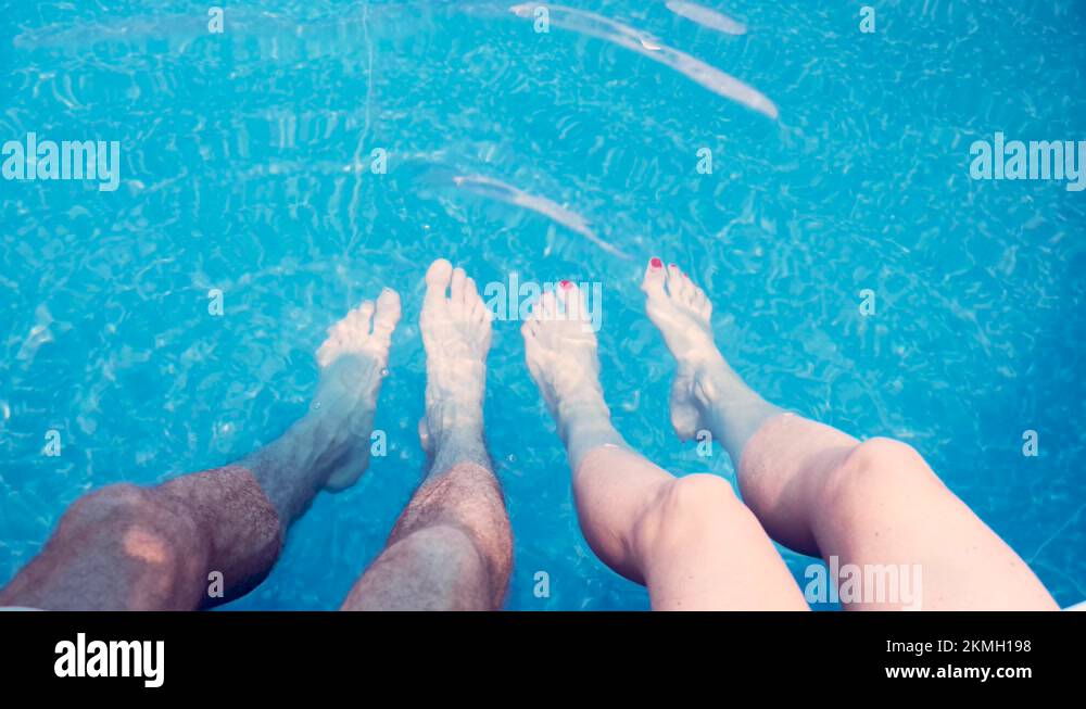 Legs in the pool water. couple dipping feet in blue pool. legs ...