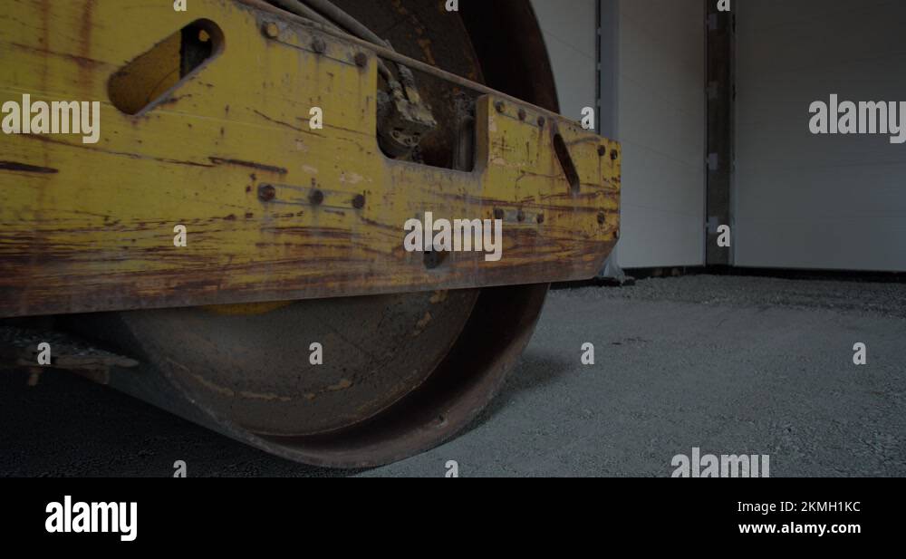 Big yellow compactor is pressing the fresh concrete at construction ...