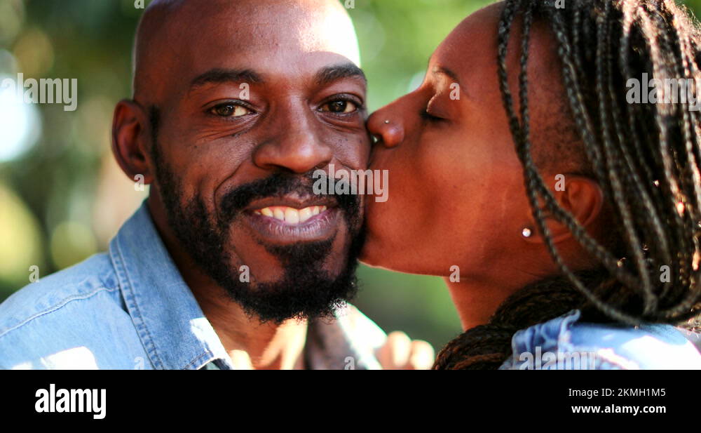 African girl kissing man in cheek outside, happy black people Stock ...