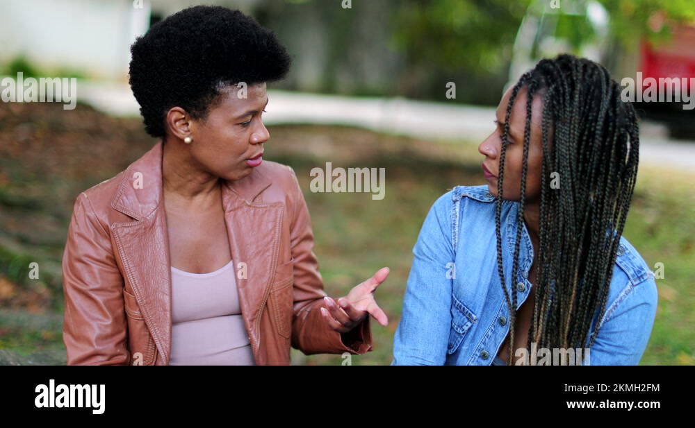 Two friends in conversation at park exchanging talk and gossip, female ...
