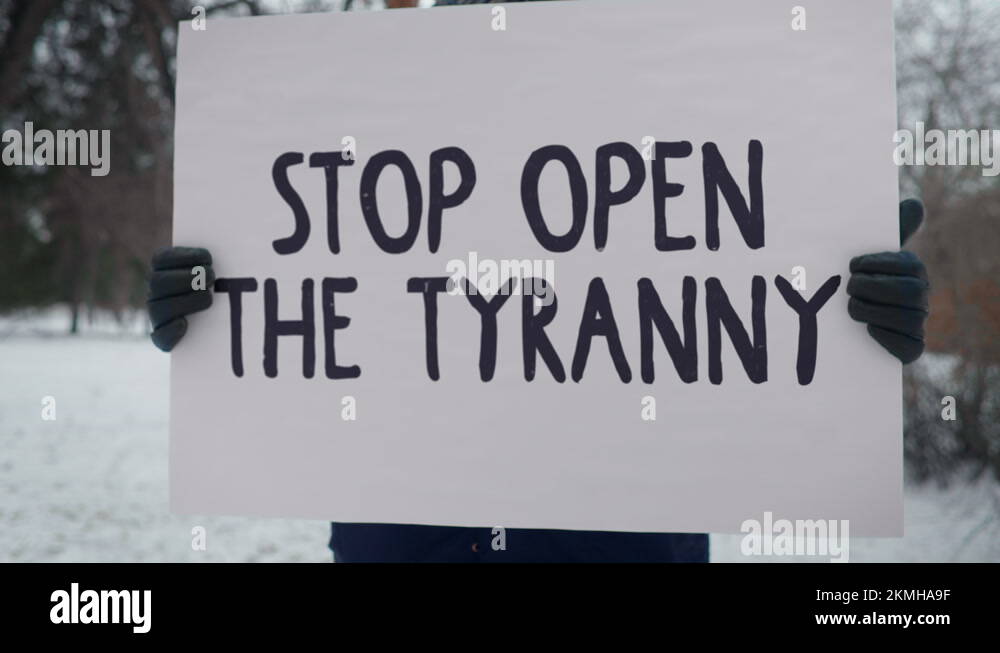 A Person is Demonstrating a Placard Stop Open the Tyranny in the Winter ...