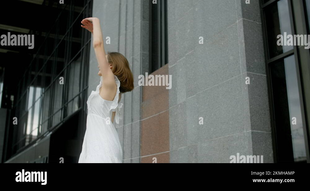 Young balerina in white dress whirls in the gallery of columns ...