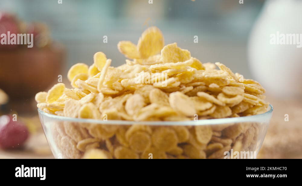Sweet crusty corn flakes falling into glass bowl. Crispy vegan cereal ...