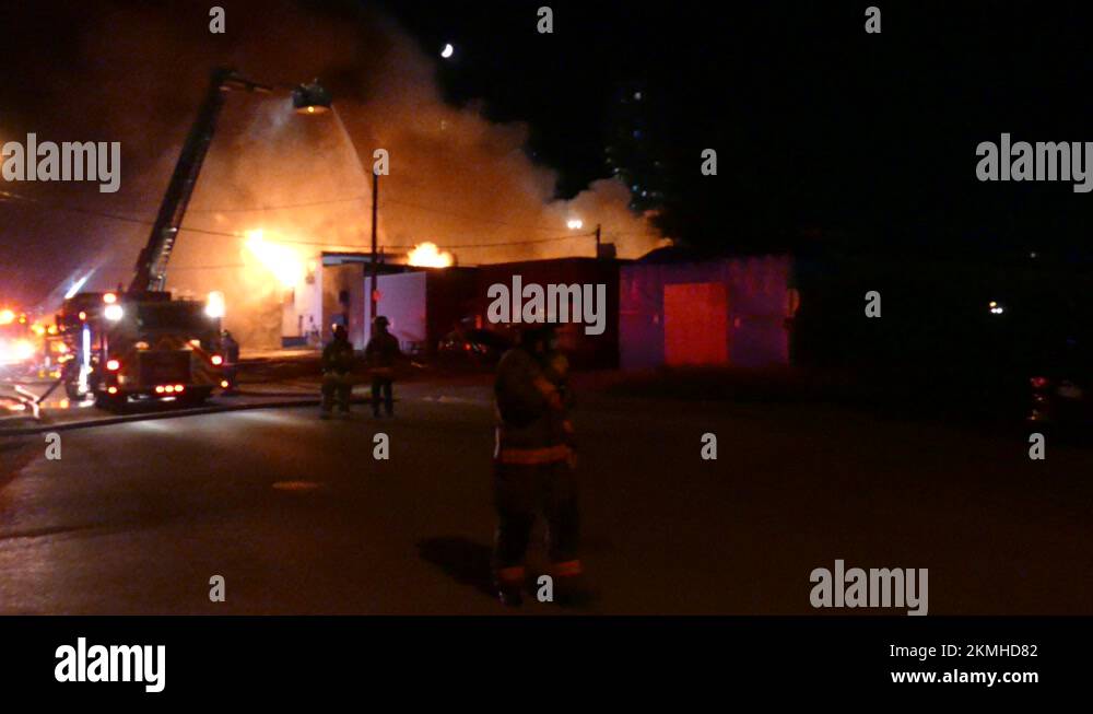 Zoom out shot from active building fire with fire gushing out of window ...