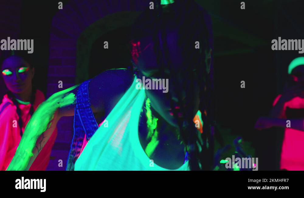 Young people with fluorescent colorful makeup and clothes dancing in UV ...