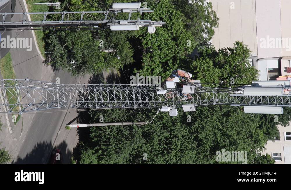Tower construction workers install radio unit and antennas on top of ...