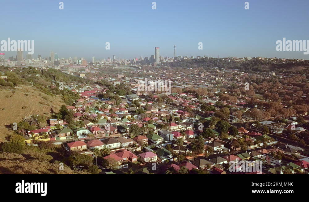 Wide aerial tracking shot of Joburg suburban houses and Johannesburg ...
