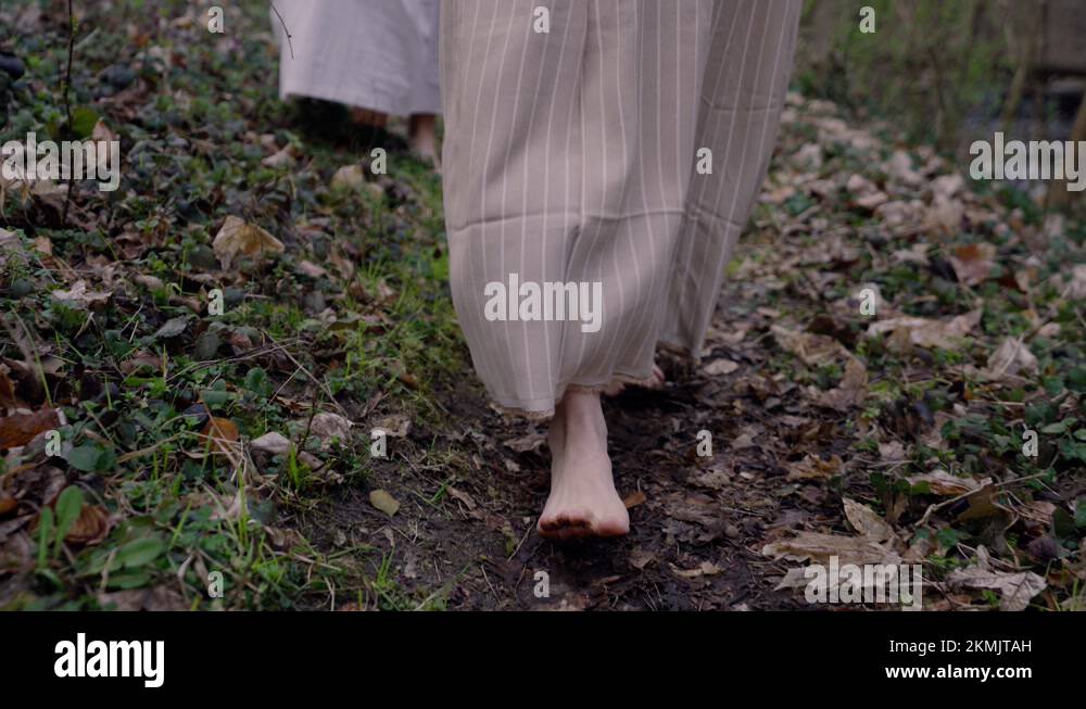 Ancient women in traditional clothing walk barefoot on a forest path ...