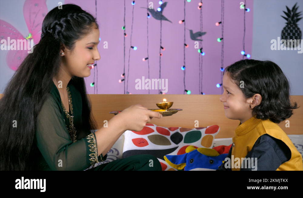 Cheerful elder sister with a Puja Thali in her hands blessing her ...