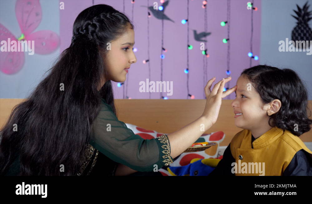 An Indian girl happily applying Tika / Tilak on her brother's forehead ...