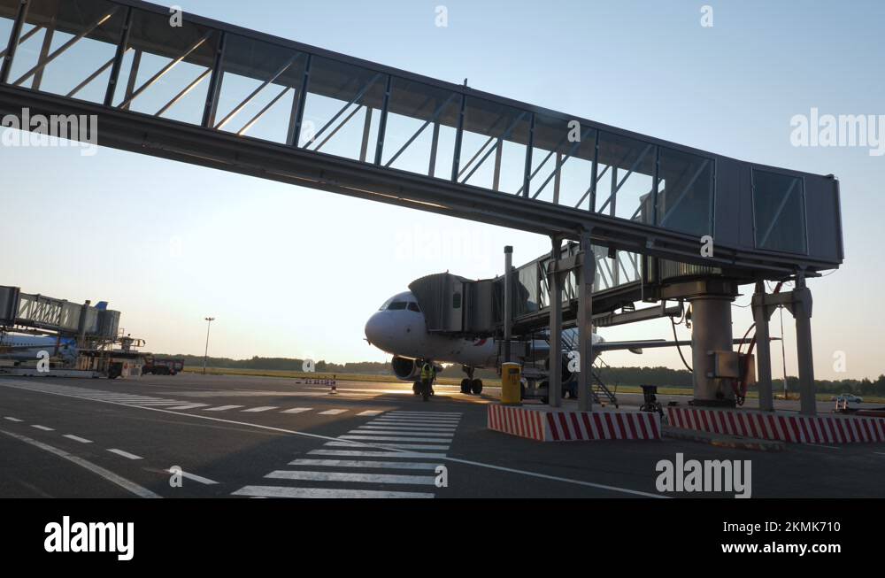 Airplane with terminal gangway of the airport building on sunset ...