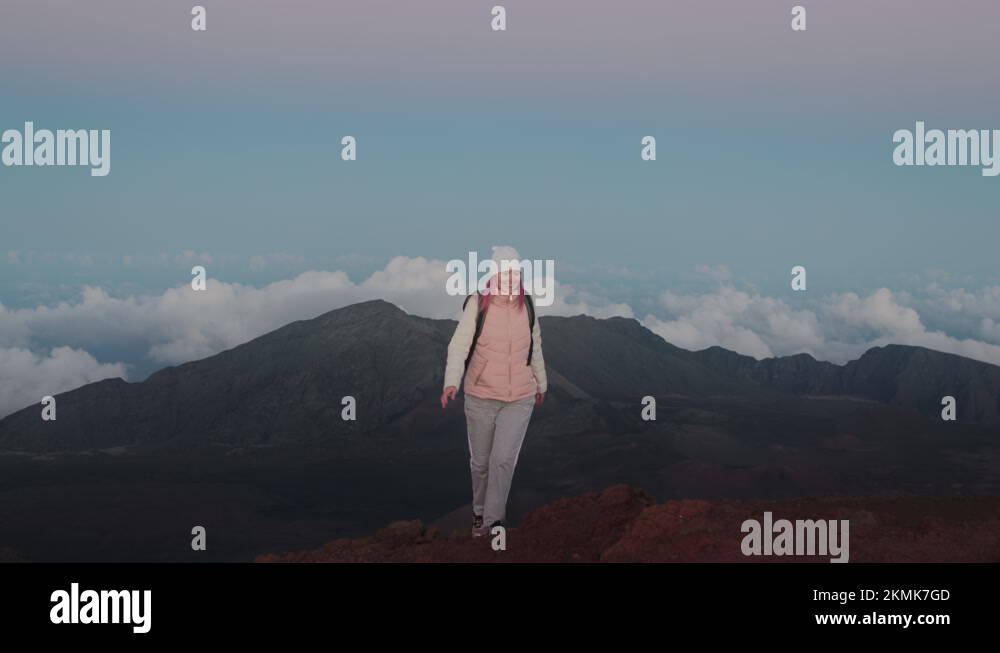 Happy smiling 30s woman hiking up Haleakala volcano mountain at pink ...