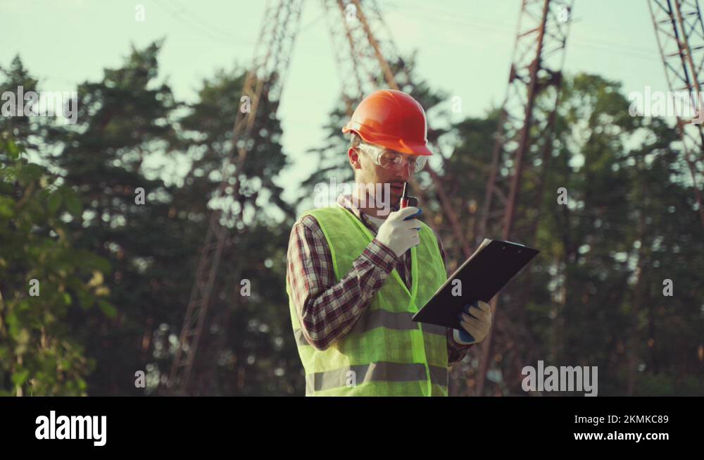 Electrical engineer wearing hard hat and safety vest checking ...