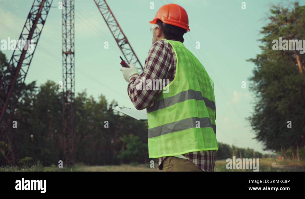 Electrical engineer wearing hard hat and safety vest checking ...